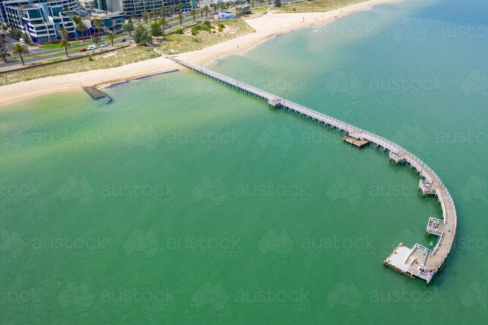 Image of Aerial view of a long curved pier out over a calm bay ...