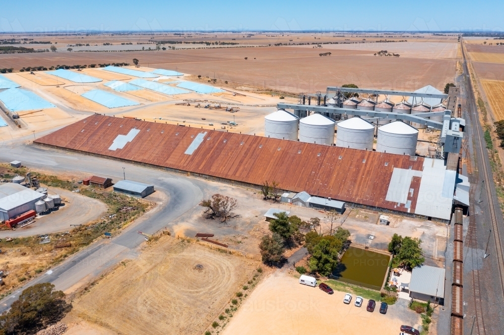 Image of Aerial view of a long grain shed alongside silos and grain ...