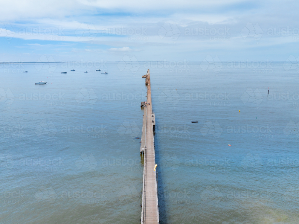 Image of Aerial view of a long narrow jetty out over a calm blue sea ...