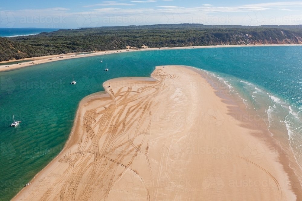 Image of Aerial view of a long sand spit covered in wheel tracks with ...