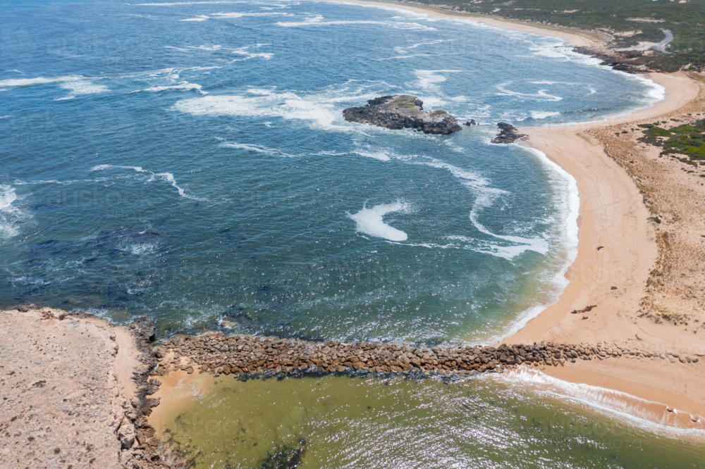 Image of Aerial view of a narrow breakwater connecting a sandy beach to ...