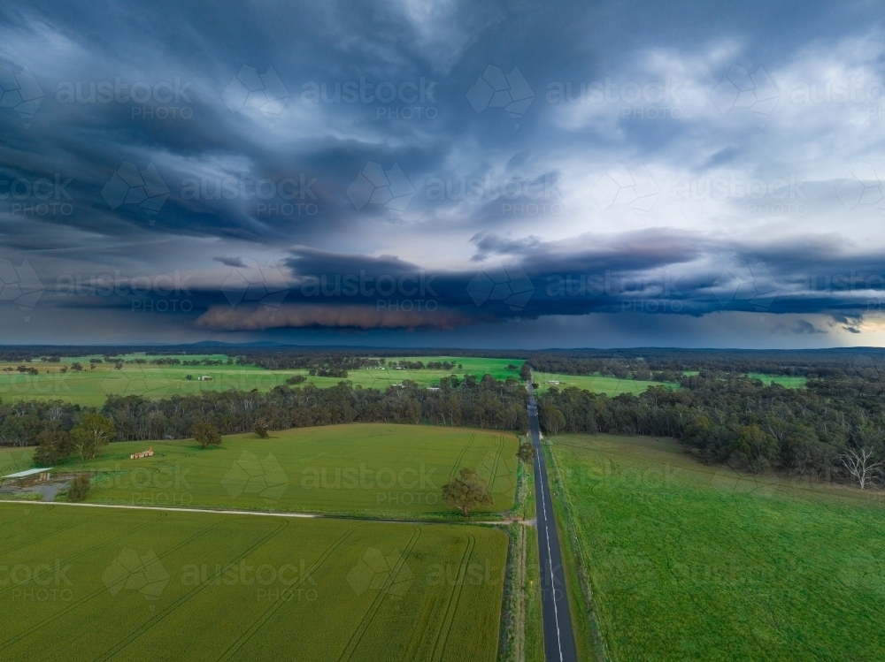 Image of Aerial view of a narrow country road running between green ...