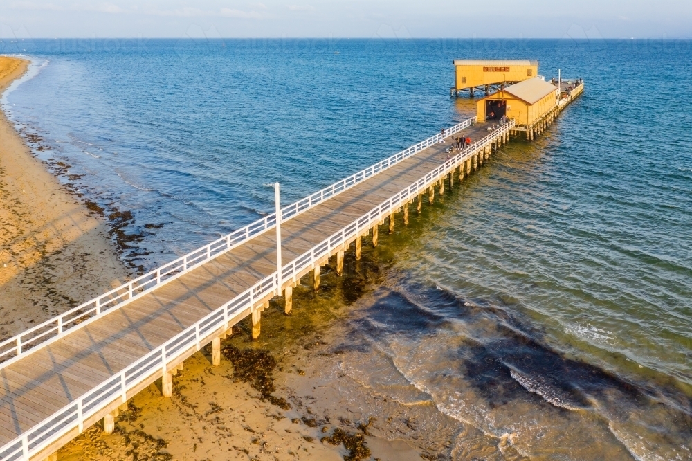Image of Aerial view of a narrow jetty off a beach going out over the ...