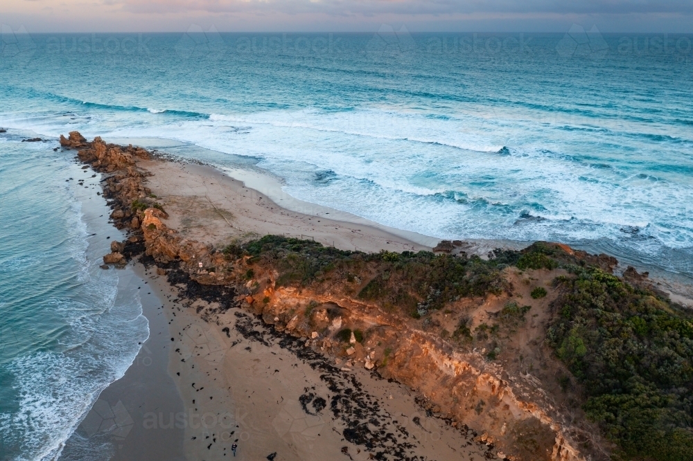 Image of Aerial view of a narrow point at twilight, with waves crashing ...