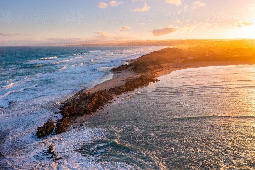 Image of Aerial view of a narrow rocky point stretching out into waves ...