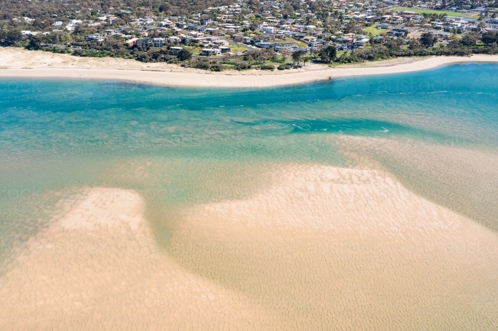 Image of Aerial view of a narrow saltwater inlet flowing past a beach ...