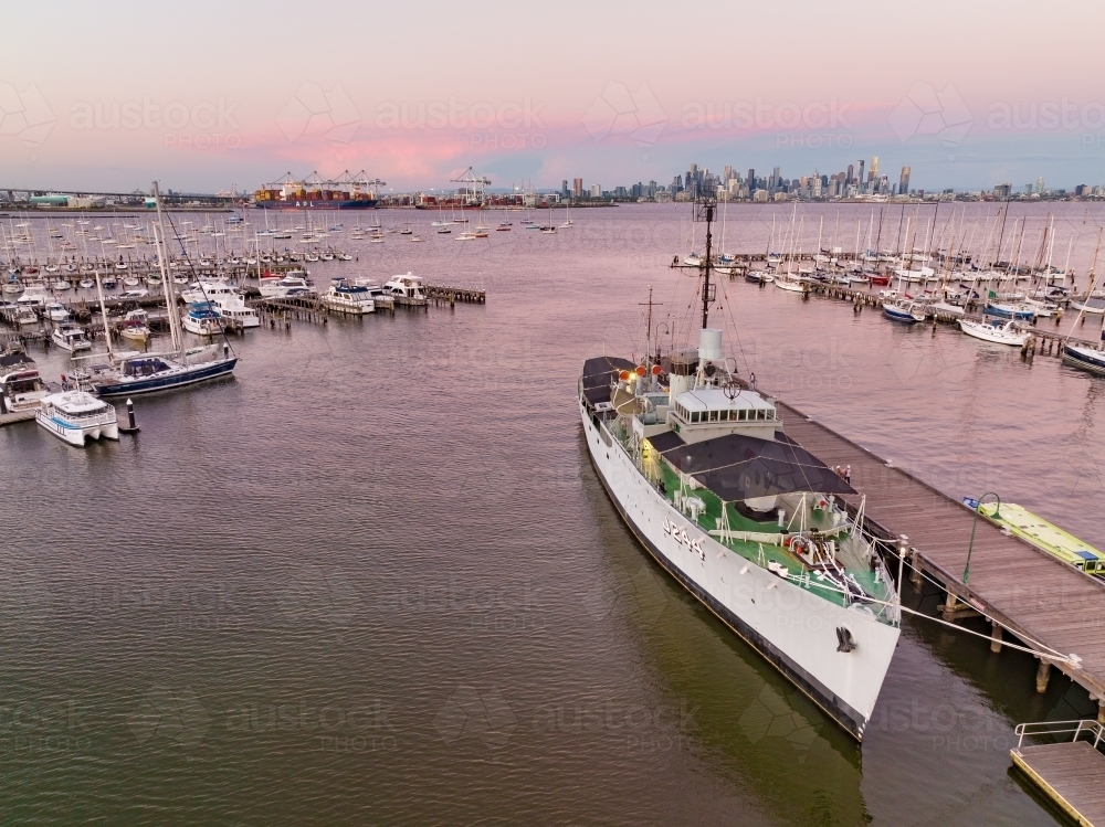 Image of Aerial view of a navy ship docked at a pier surrounded by ...