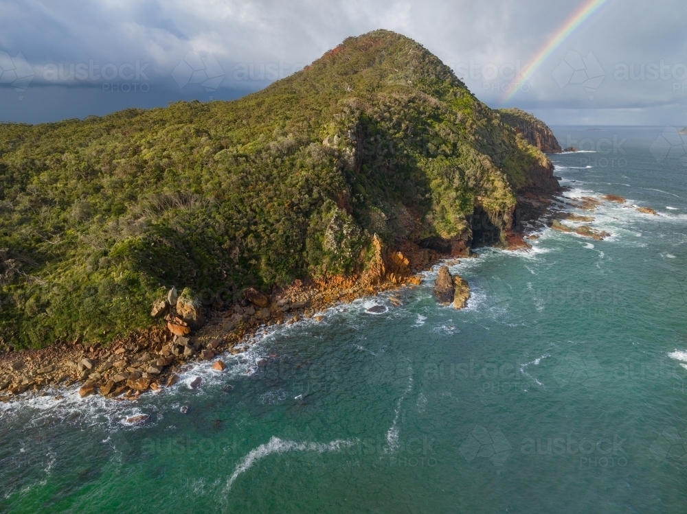 Image of Aerial view of a rainbow over a coastal headland with dramatic ...