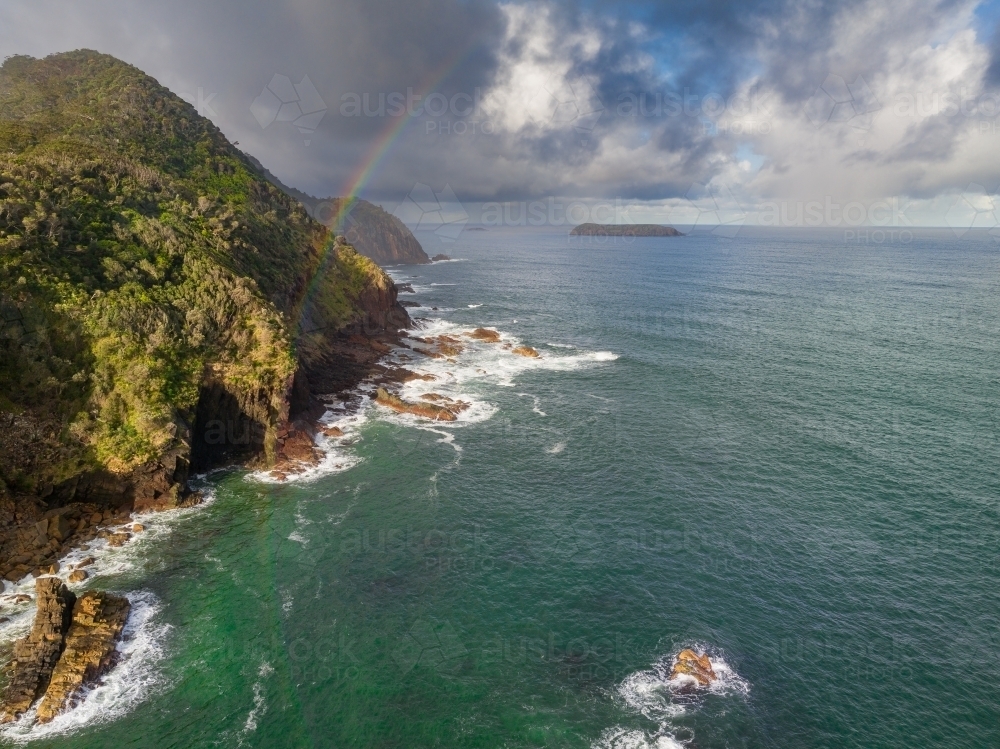 Image of Aerial view of a rainbow over a rugged coastal headland with ...