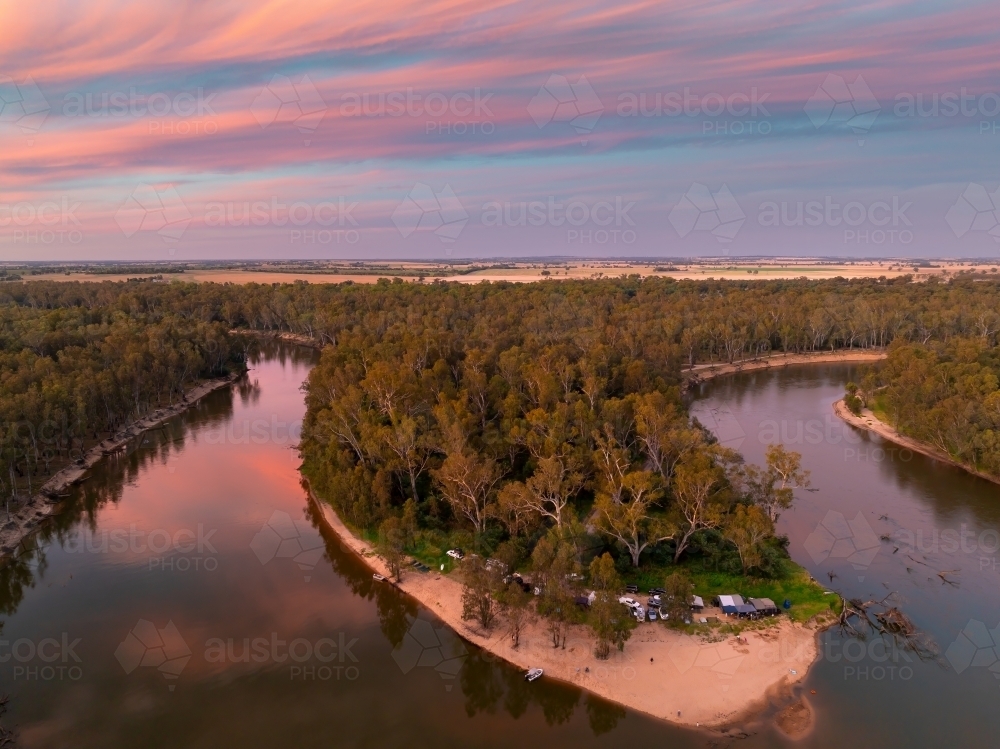 Image of Aerial view of a river bend lined with trees and a colourful ...