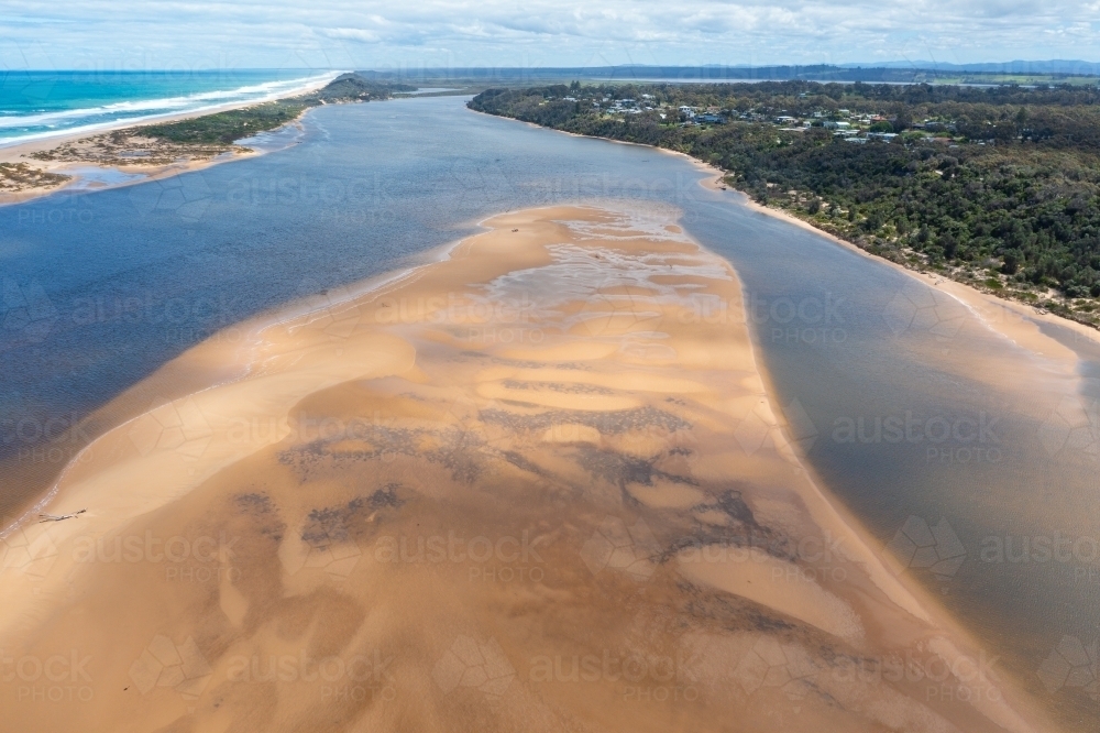 Image of Aerial view of a river flowing around a large sandbar covered ...