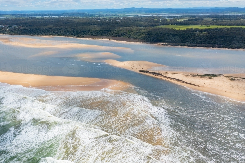 Image of Aerial view of a river flowing out to sea and waves breaking ...