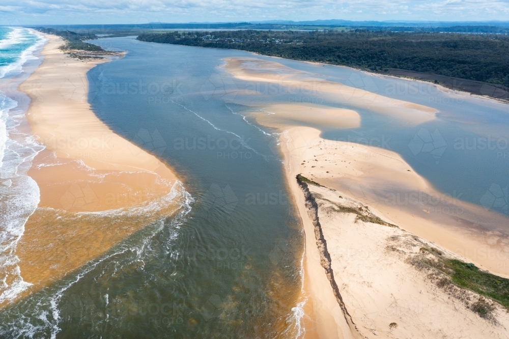 Image of Aerial view of a river flowing out to sea through a sandy ...