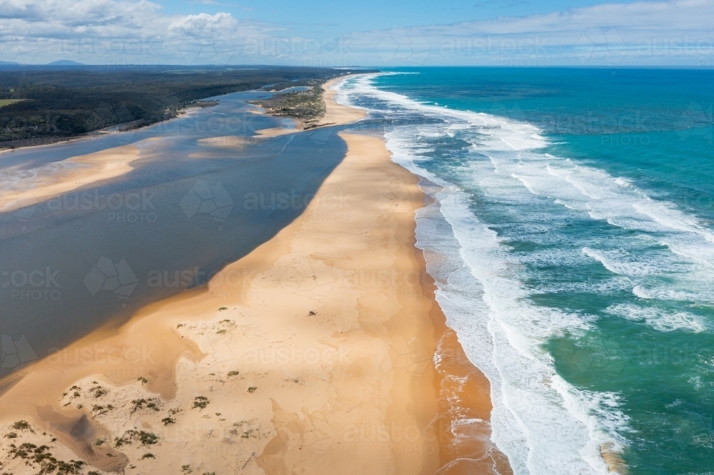 Image of Aerial view of a river flowing out to sea through a sandy ...