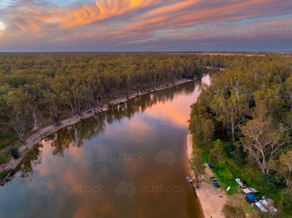 Image of Aerial view of a river lined with trees and a colourful sunset ...