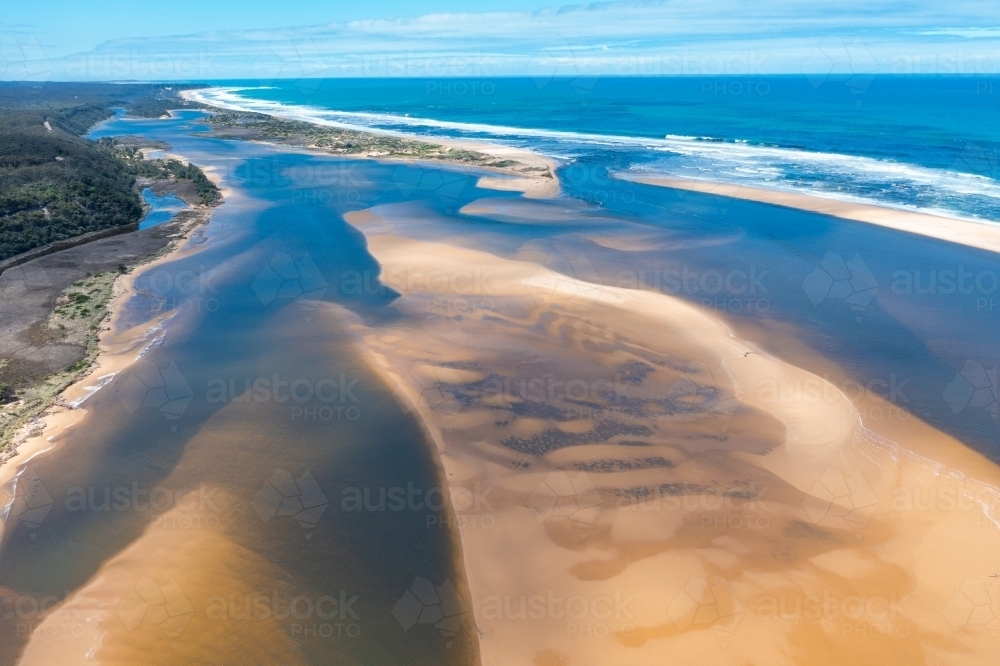 Image of Aerial view of a river running next to a sandy beach then out ...