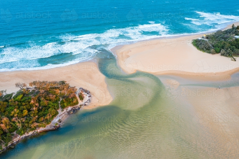 Image of Aerial view of a river winding its way over a sandy beach and ...