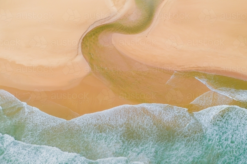 Image of Aerial view of a river winding its way over a sandy beach and ...
