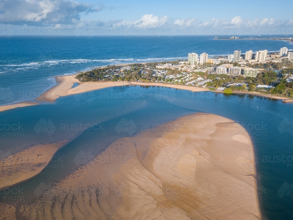 Image of Aerial view of a river winding out to the ocean past a city ...