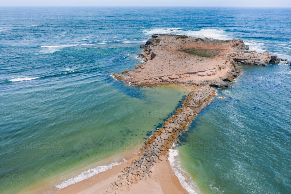 Image of Aerial view of a rocky island connected to a beach with a rock ...