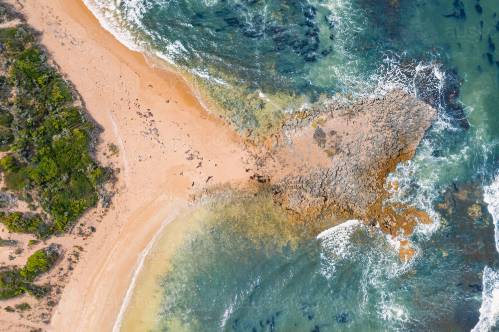 Image of Aerial view of a rocky island off the point of a sandy beach ...