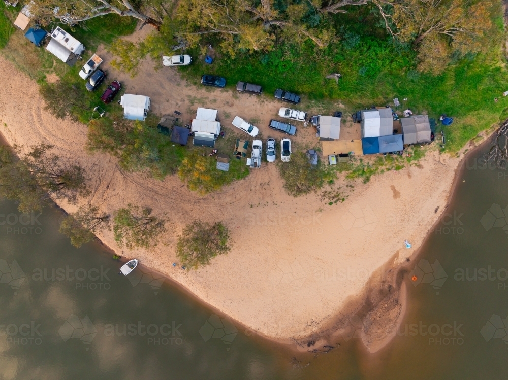 Image of Aerial view of a row of caravans and tents on a sandy beach ...