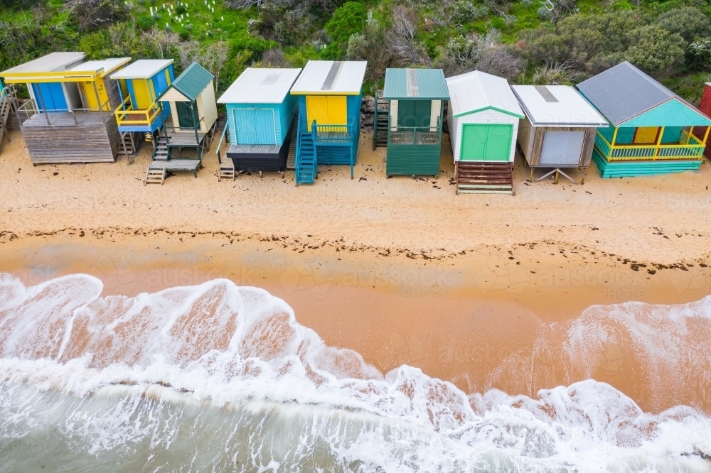 Image of Aerial view of a row of colourful beach huts with waves ...