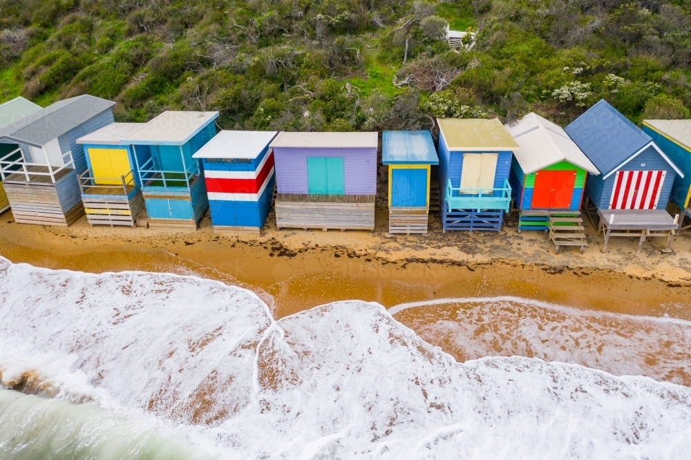 Image of Aerial view of a row of colourful beach huts with waves ...