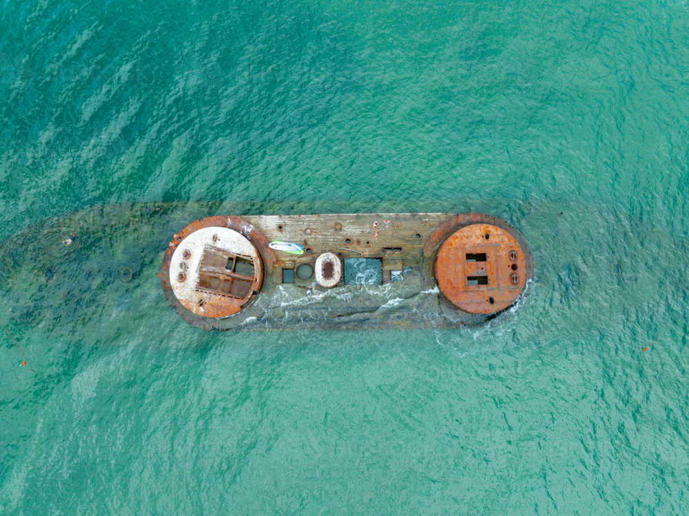 Image of Aerial view of a rusty shipwreck in a shallow coastal bay ...