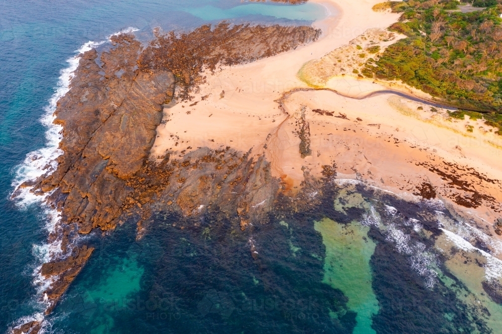 Image of Aerial view of a sandy coastal point surrounded by rocks and ...