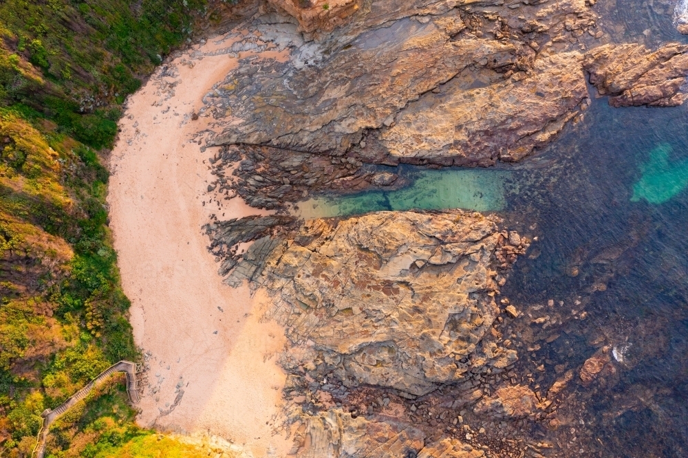 Image of Aerial view of a secluded beach alongside wide rock ledges in ...