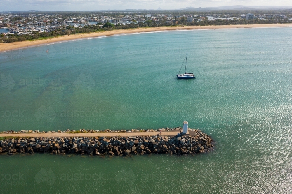 Image of Aerial view of a solitary yacht anchored on a calm bay near a ...