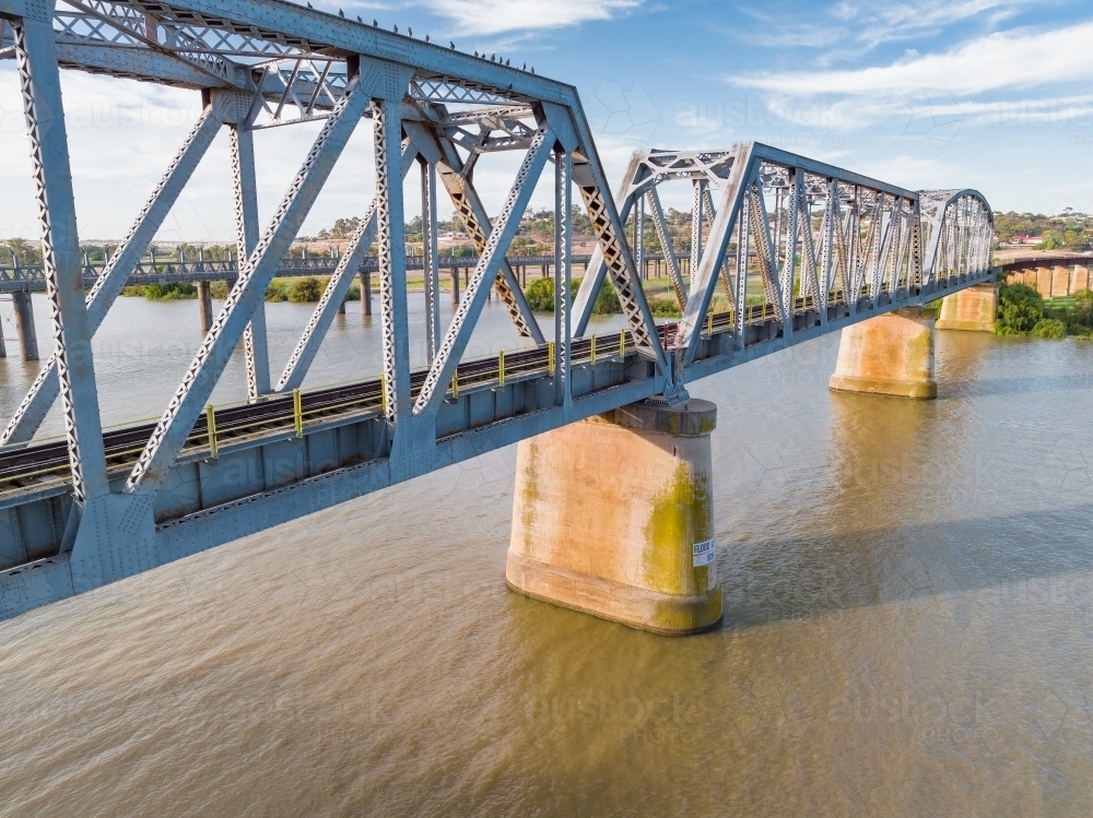 Image of Aerial view of a steel span bridge crossing a wide brown river ...