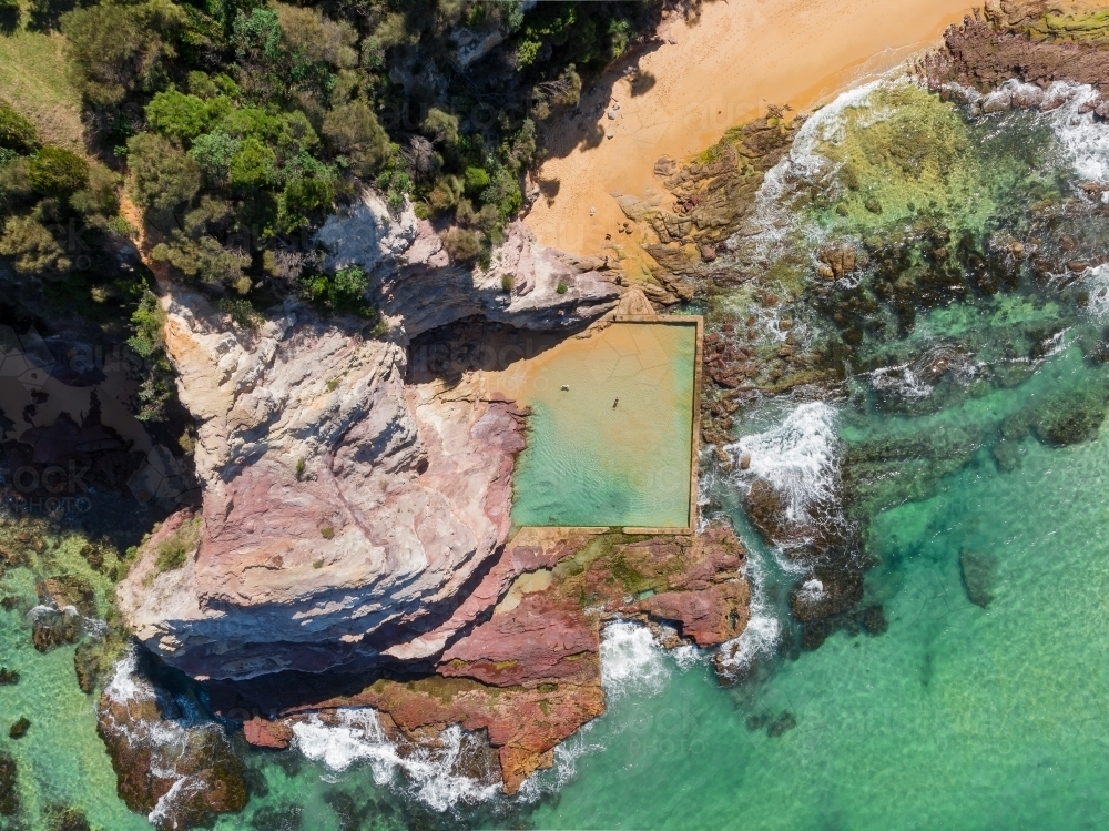 Image of Aerial view of a swimming rock pool alongside a beach and ...