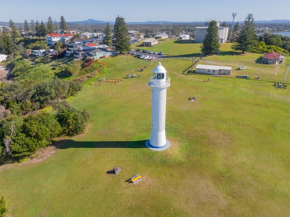 Image of Aerial view of a tall white lighthouse on a grassy coastal ...