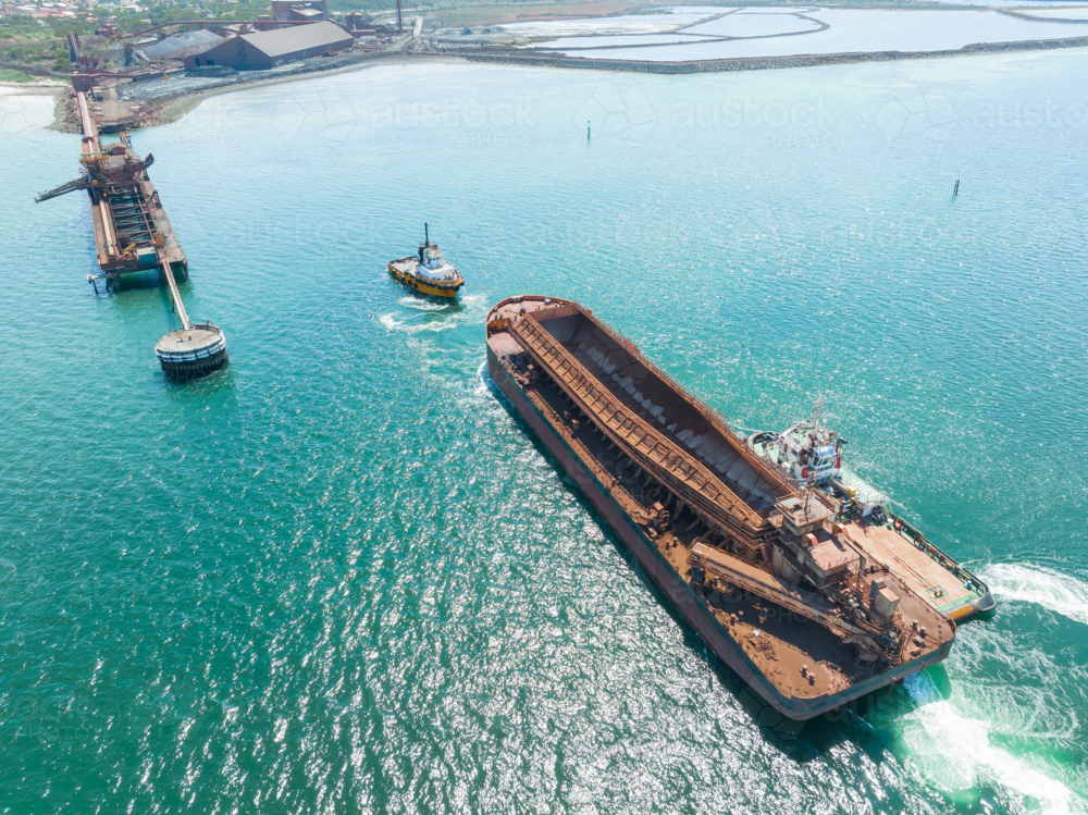 Image of Aerial view of a tugboat pulling a bulk ore ship into port ...