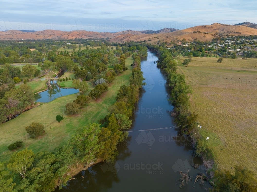 Image of Aerial view of a wide river flowing alongside a golf course ...
