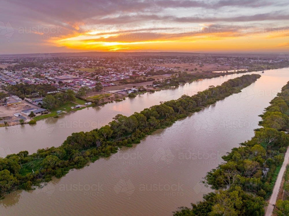 Image of Aerial view of an island up the middle of a wide brown river ...