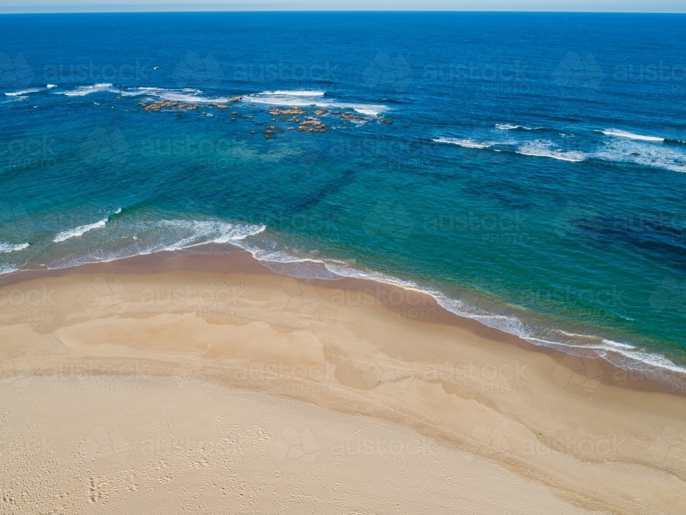 Image of Aerial view of beach sand and ocean water with rocks at low ...
