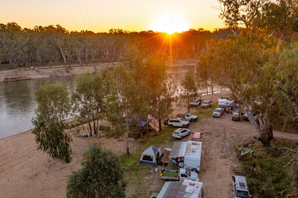 Image of Aerial view of caravans camped under gum trees on riverbank at ...
