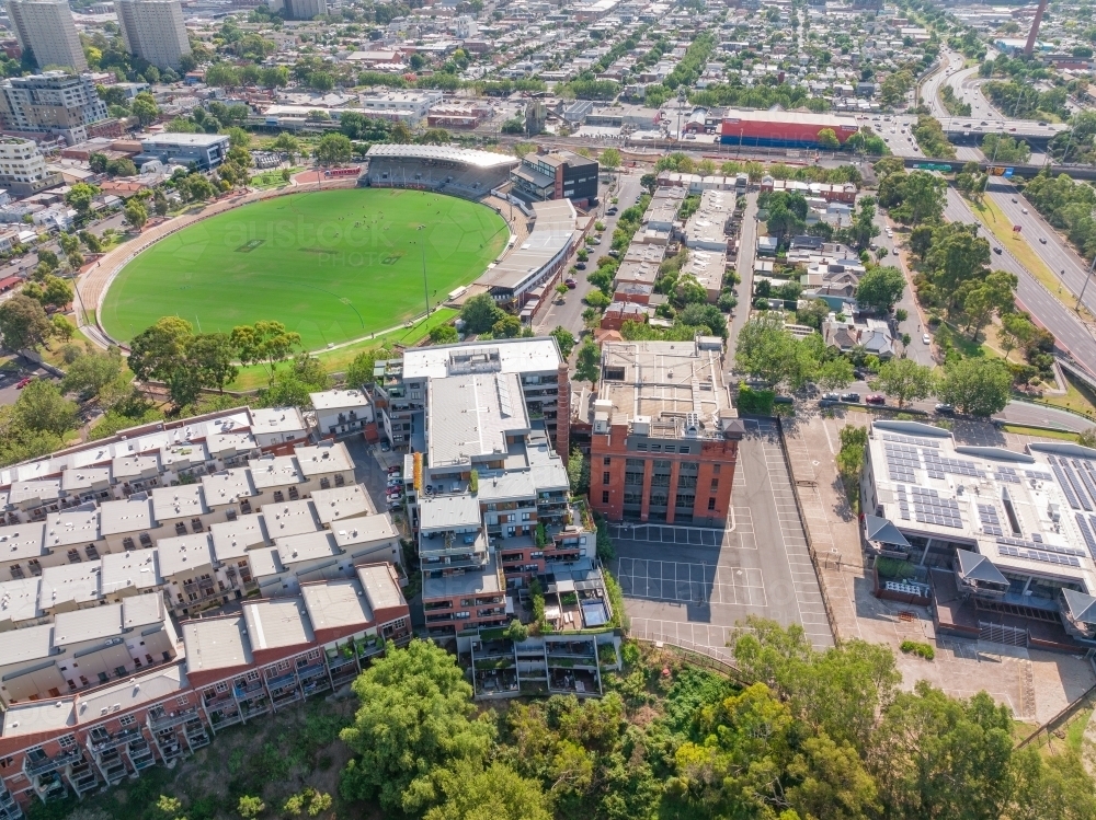 Image of Aerial view of city buildings surrounding a sports oval ...