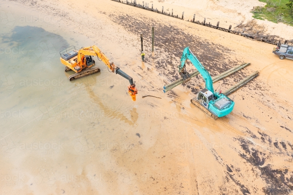Image of Aerial view of colourful diggers carrying poles along a sandy ...
