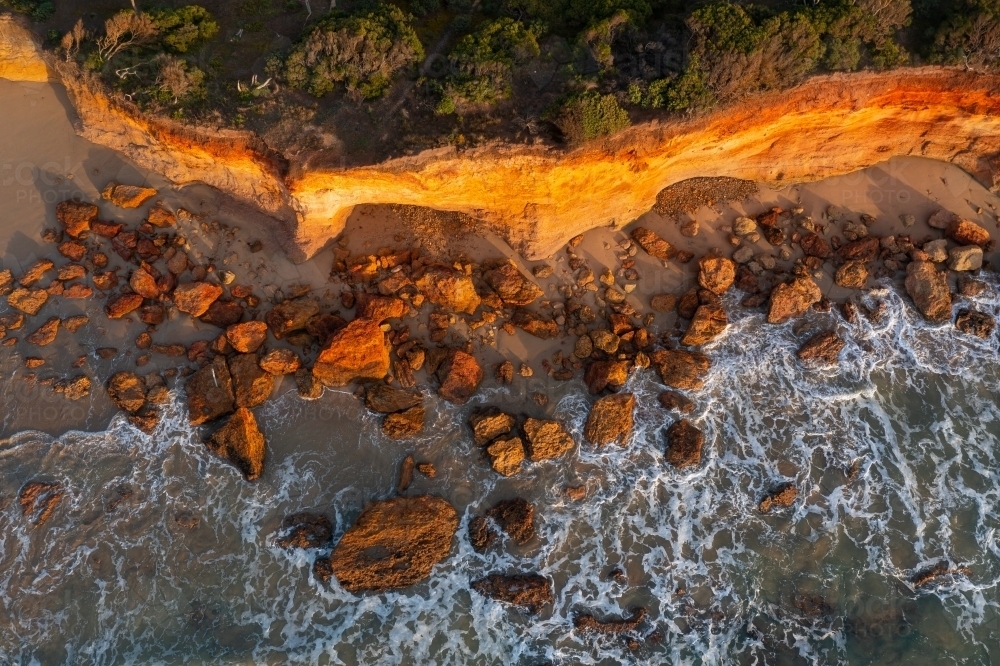 Image of Aerial view of crumbling coastal cliffs catching golden dawn ...