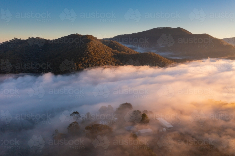 Image of Aerial view of early morning light on clouds of fog over an ...