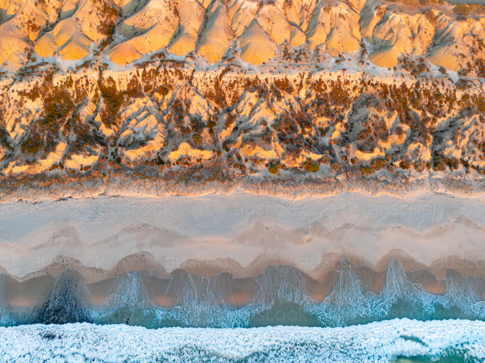 Image of Aerial view of eroded cliffs above a sandy coastline at sunset ...