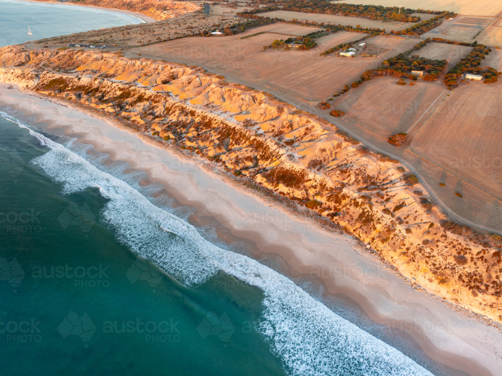 Image of Aerial view of eroded cliffs above a sandy coastline at sunset ...