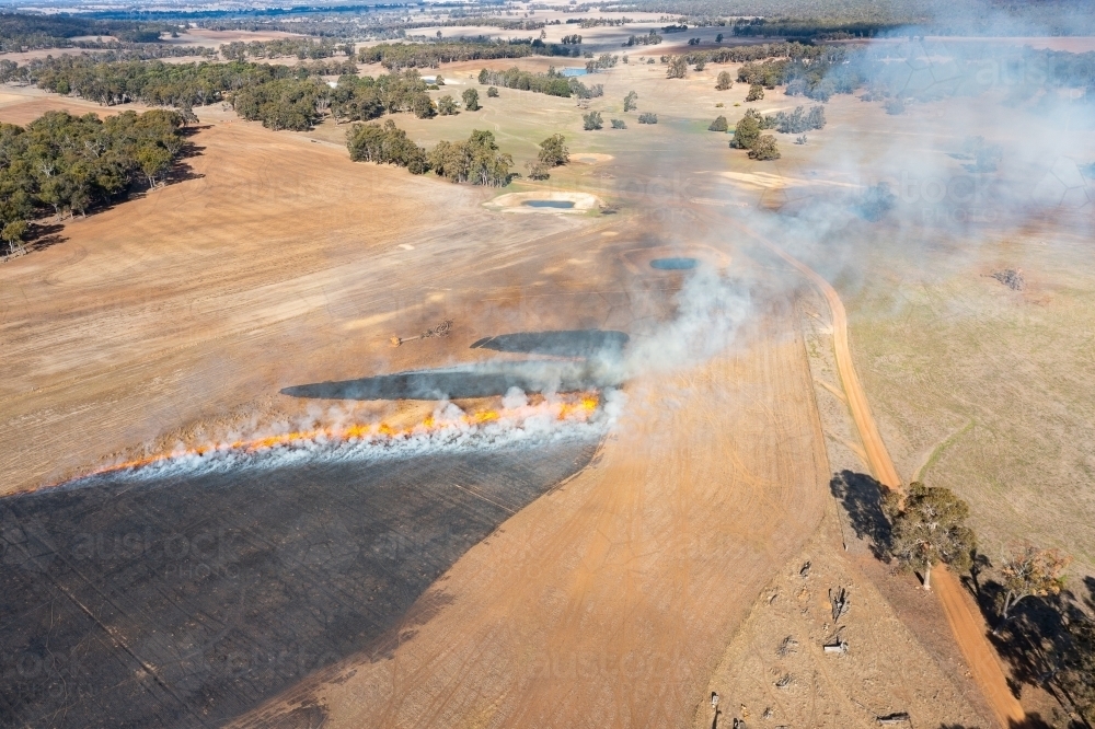 Image of Aerial view of farmland with fire burning - Austockphoto