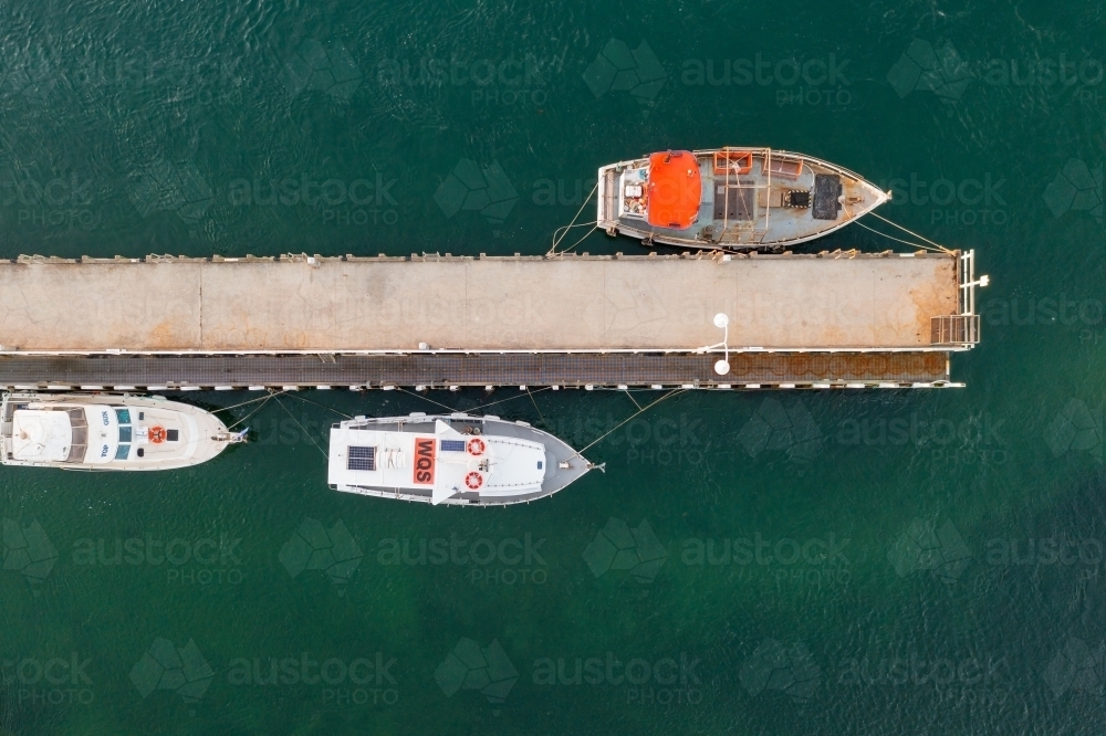 Image of Aerial view of fishing boats docked alongside a jetty over a ...
