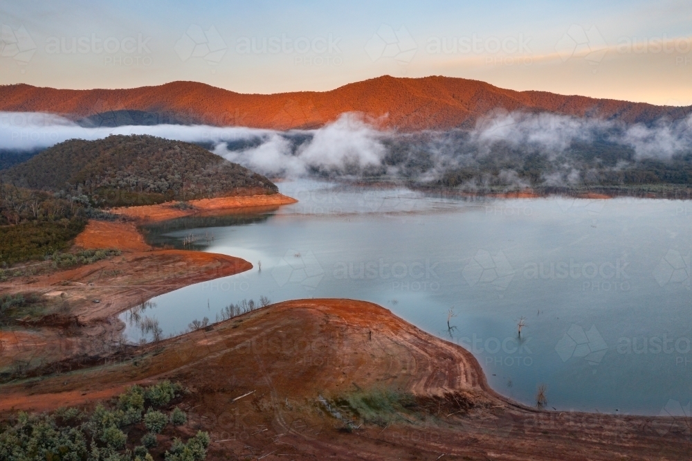 Image of Aerial view of fog patches lifting from a lake surrounded by ...