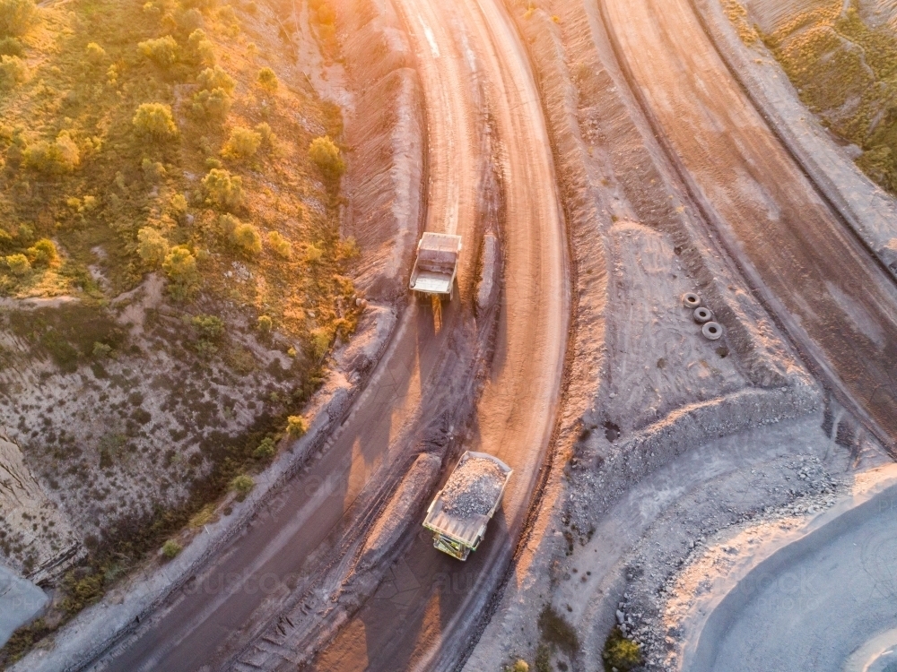 Image of Aerial view of full and empty dump trucks passing one another ...